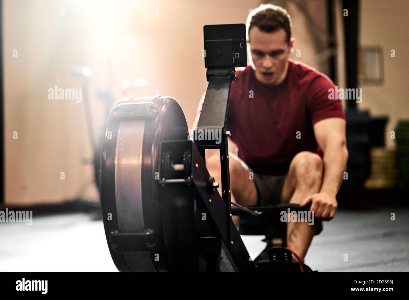 Fit young man in sportswear using a rowing machine during a lone ...