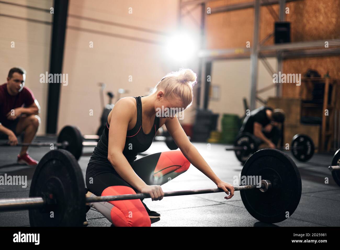 Fit young woman in sportswear getting ready to lift heavy weights ...