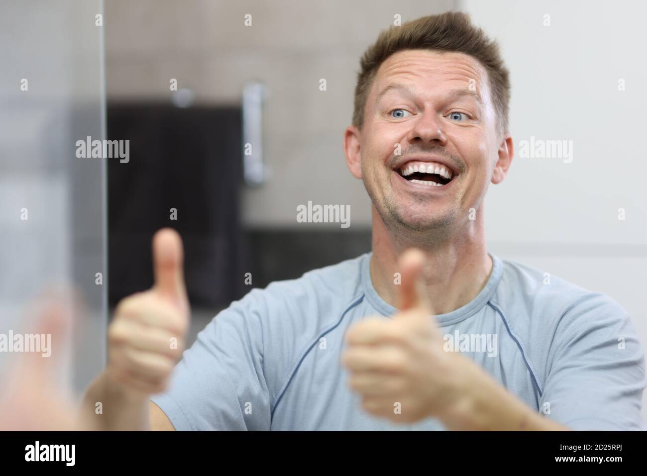 Young handsome man looks in mirror and shows thumbs up Stock Photo - Alamy