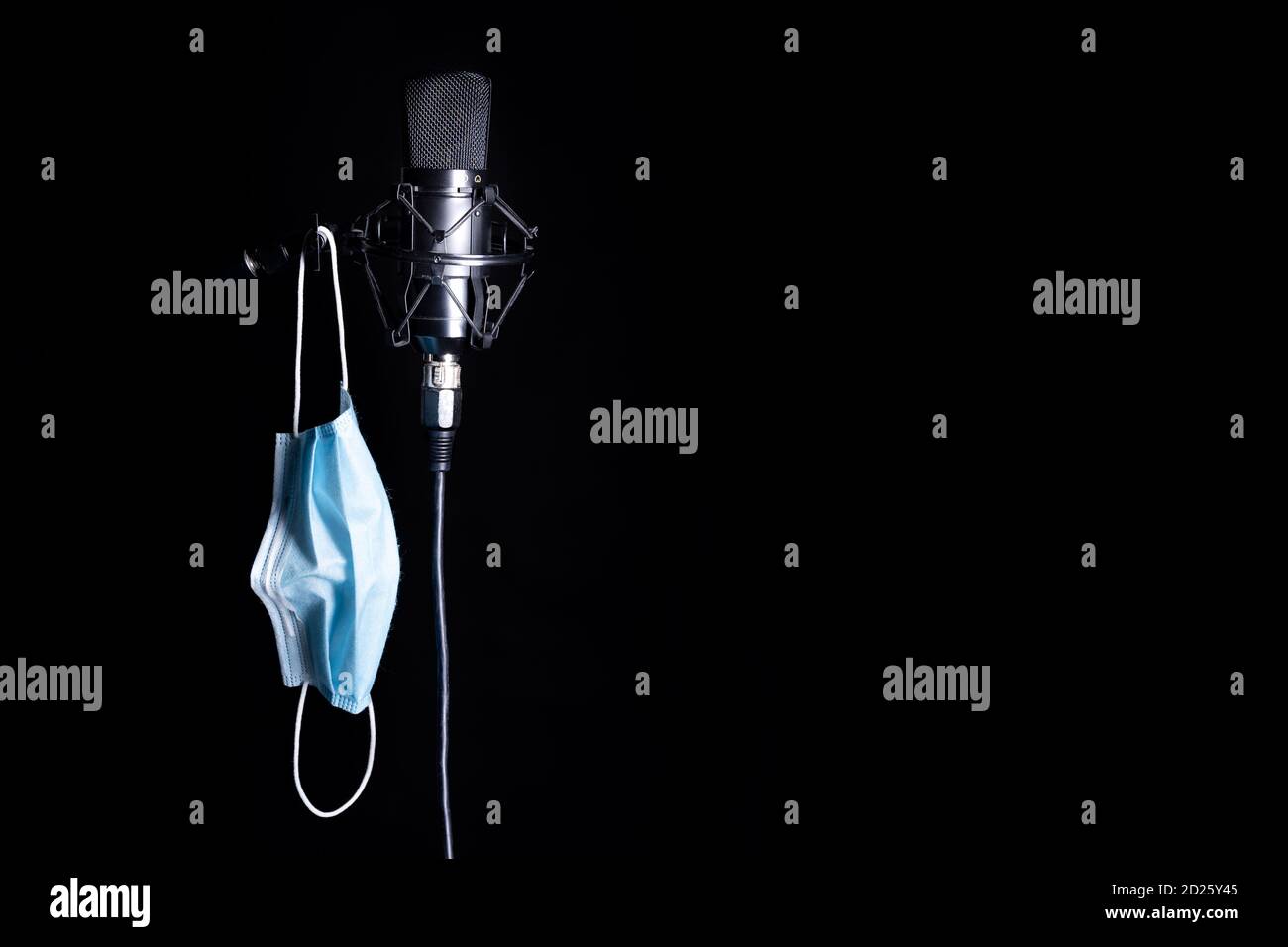 Condenser microphone in its holder next to a mask hanging on the holder ...