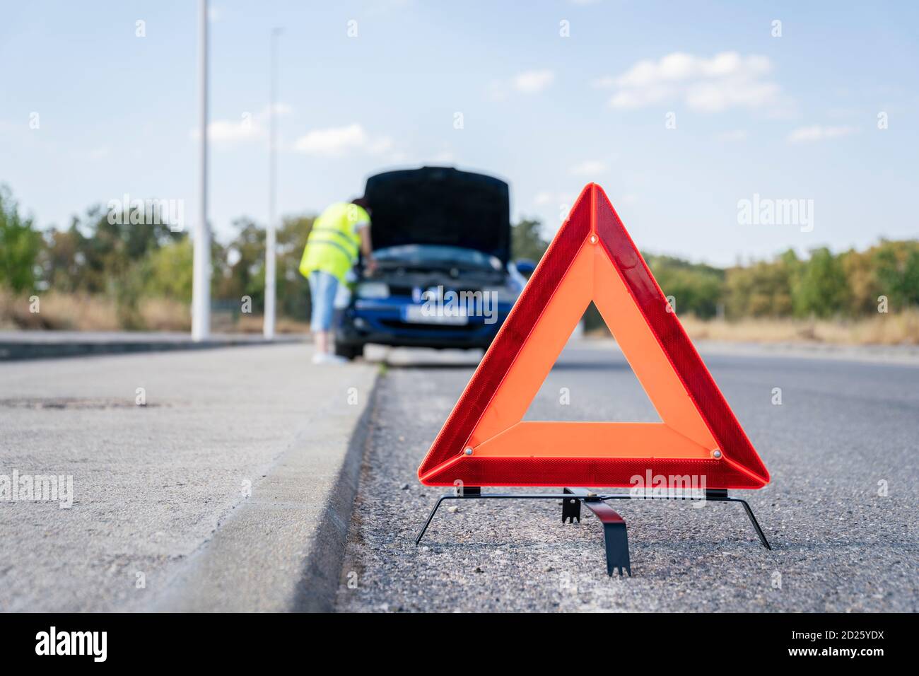 Road breakdown signaling triangle with broken down car in the ...