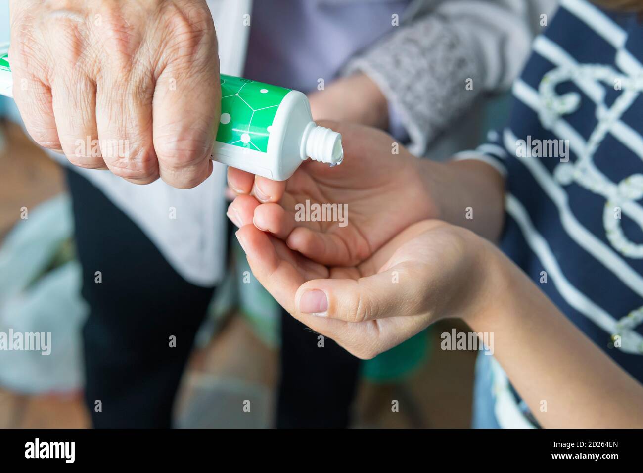grandma pours gel on granddaughter's hands. Hand applying alcohol spray ...