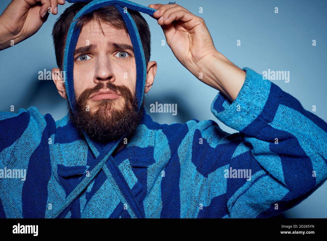 A man in a blue robe on a light background gestures with his hands ...