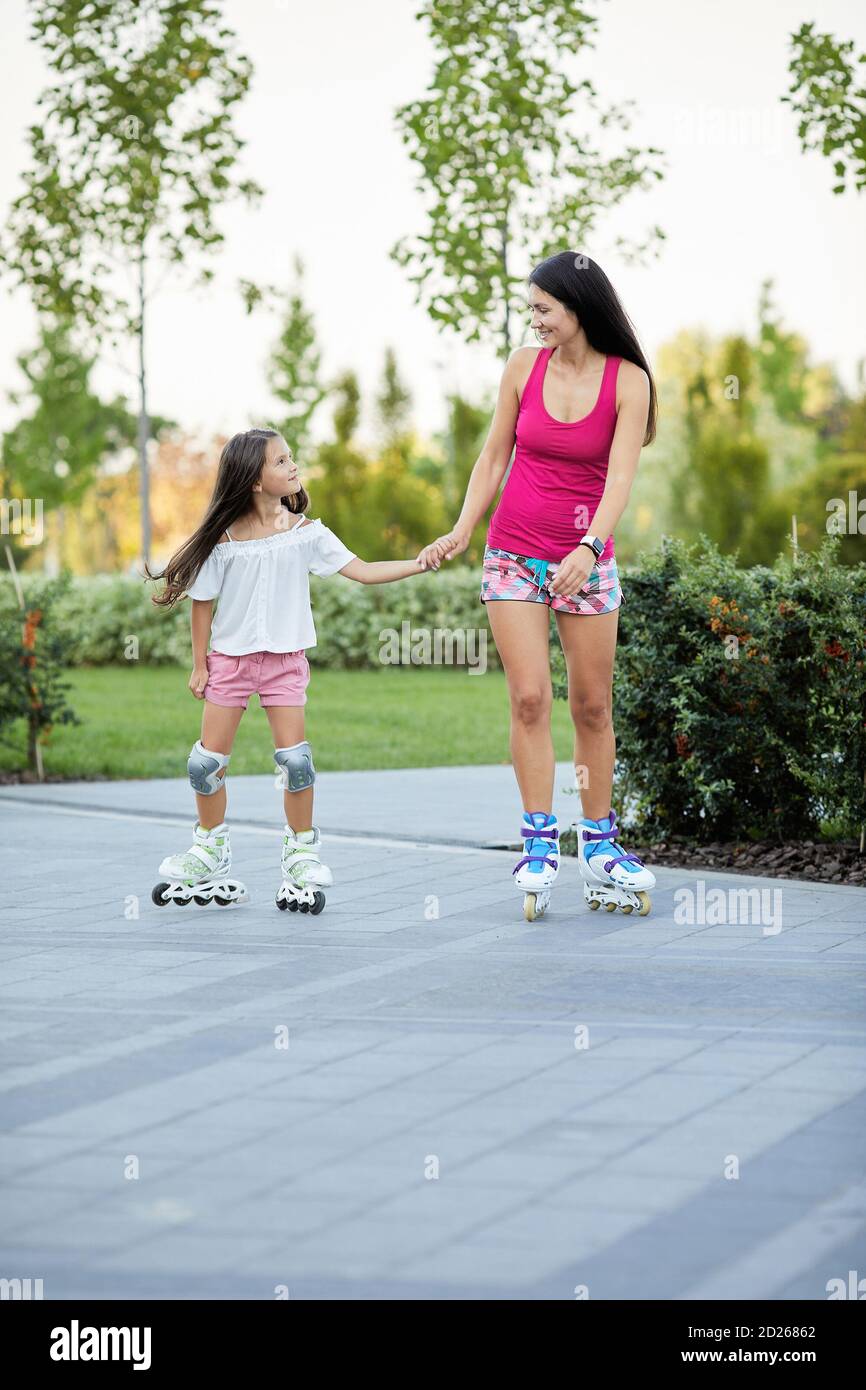 Young mother and her little daughter rollerskating in park. family ...
