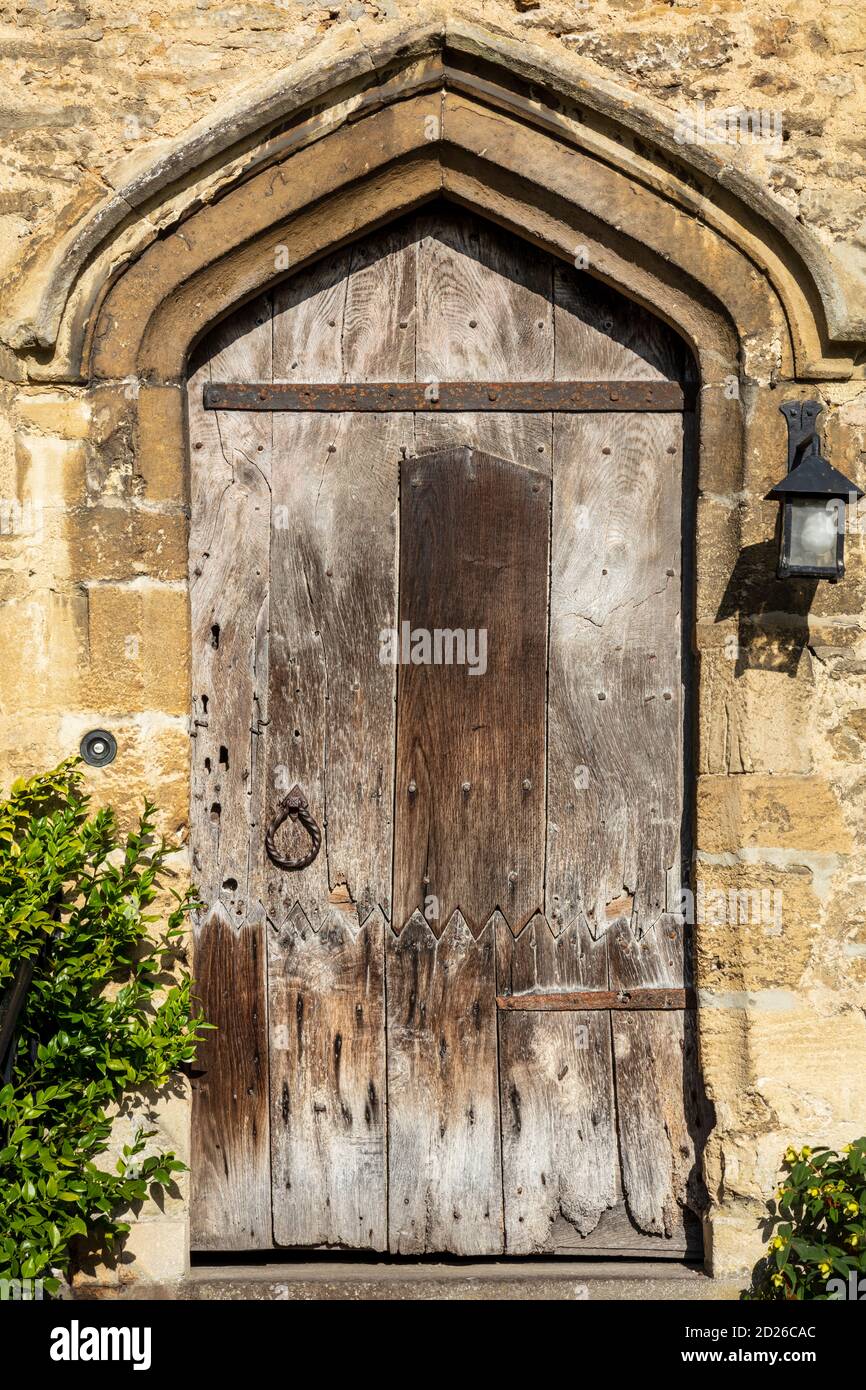 An old, medieval wooden door at the entrance to a traditional Cotswold ...