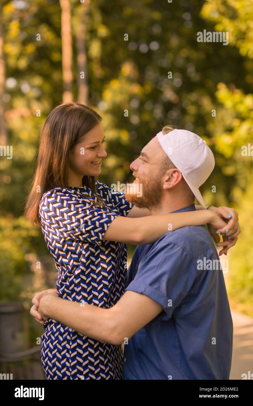 Girl hugging in mans arms standing, in park Stock Photo - Alamy