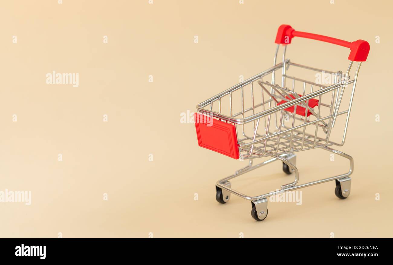 Empty red shopping cart or trolley on beige background with copy space ...