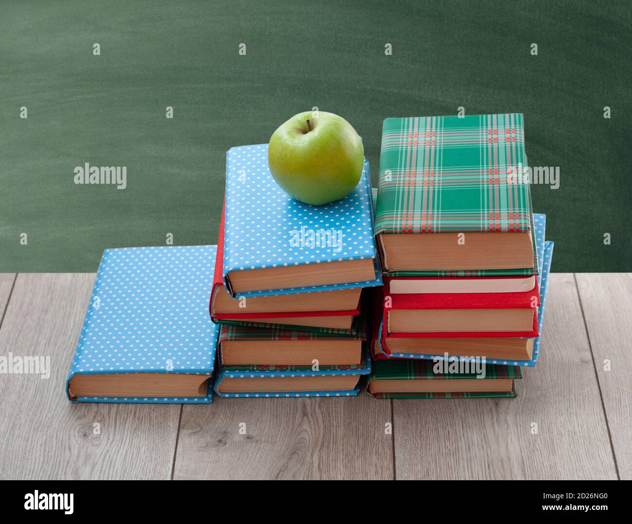 Back to school, pile of books in colorful covers and green apple on ...