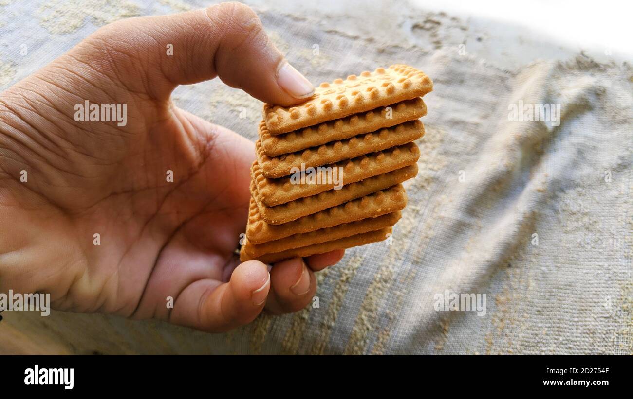 Man holding many biscuits in hand. Many Brown wheat biscuits with tea ...
