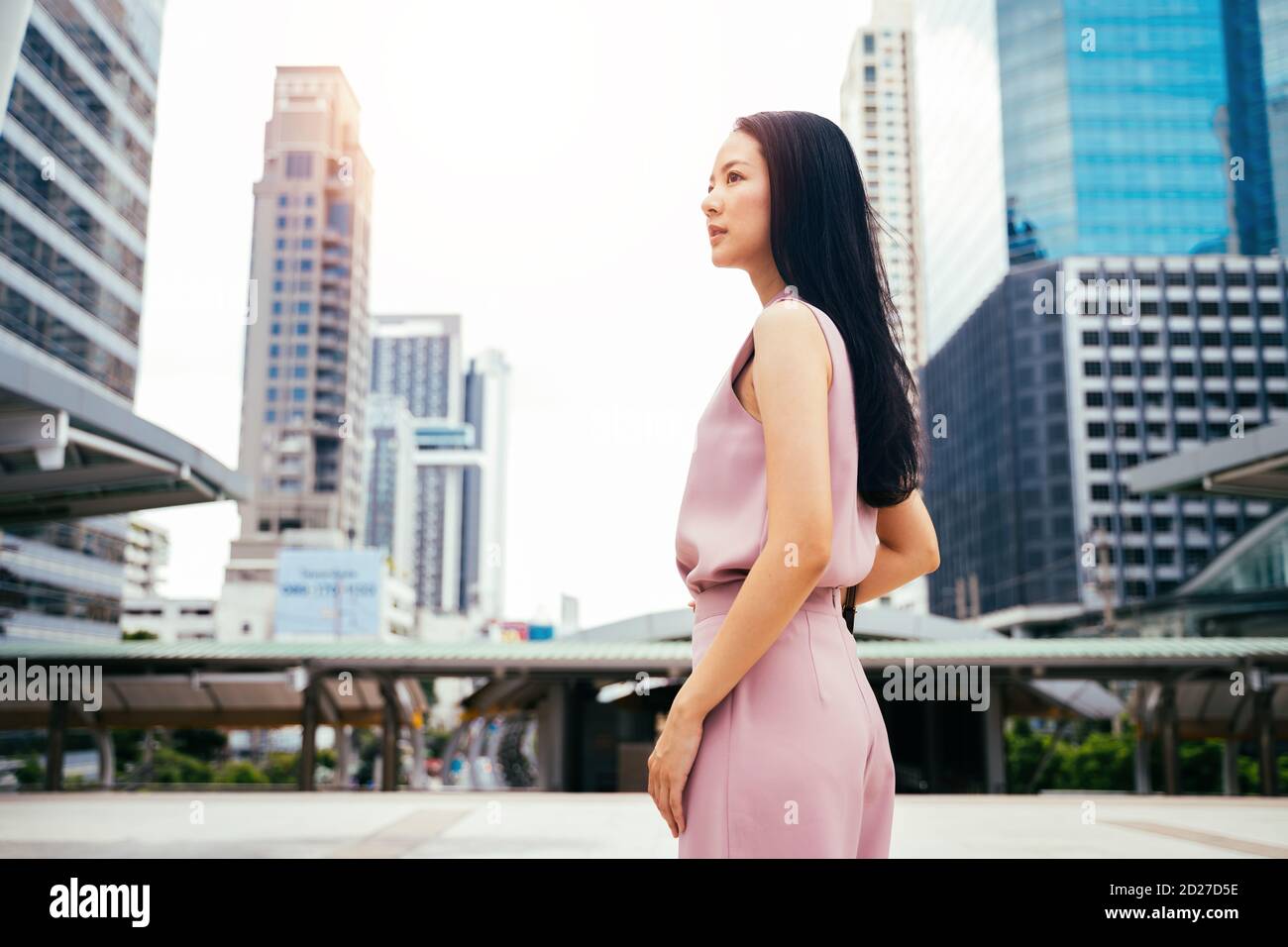 Businesswoman looking across towards city with tall modern buildings ...