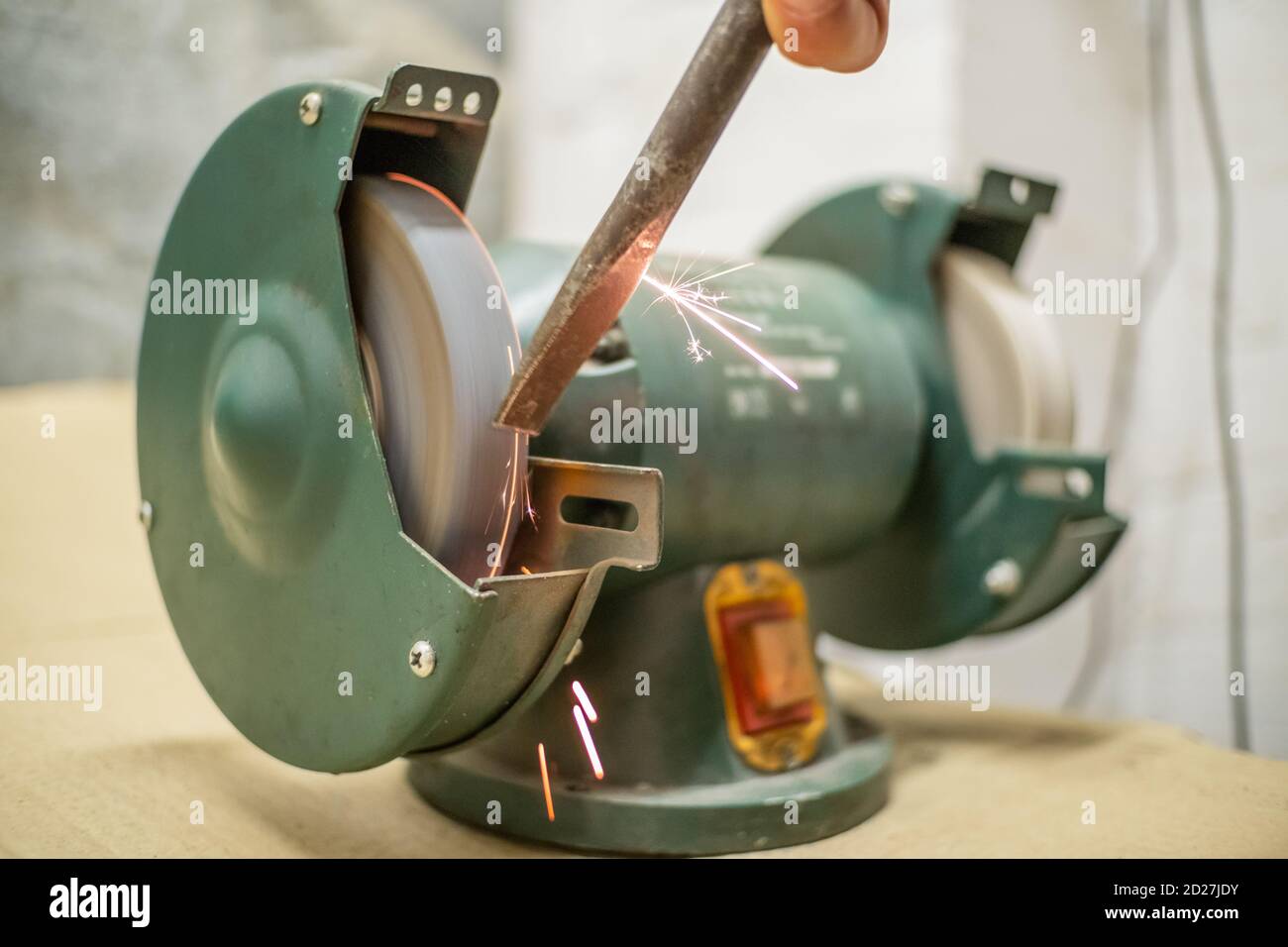 master sharpens a chisel on a grinding machine Stock Photo - Alamy