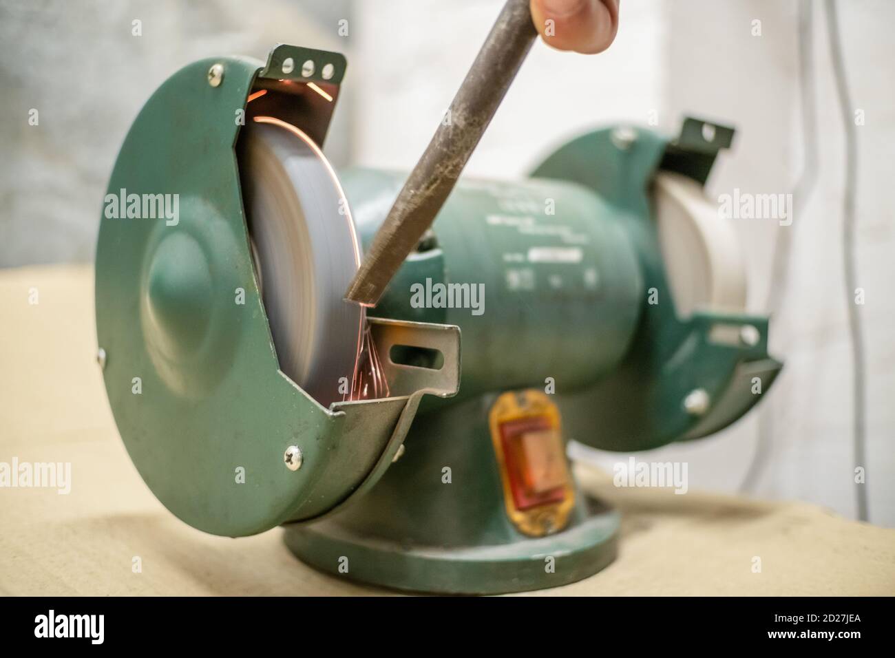 master sharpens a chisel on a grinding machine Stock Photo - Alamy