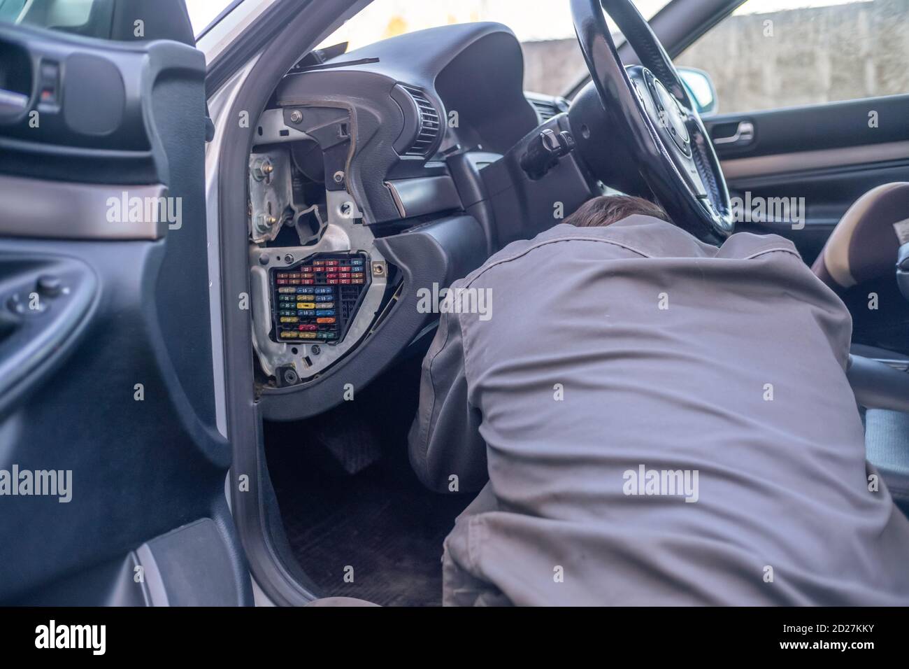 Male car mechanic looking under the steering space inside the car ...