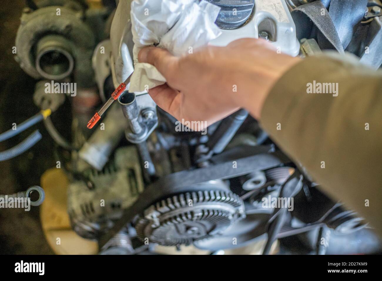 An auto mechanic checks the oil level in a car engine during routine ...