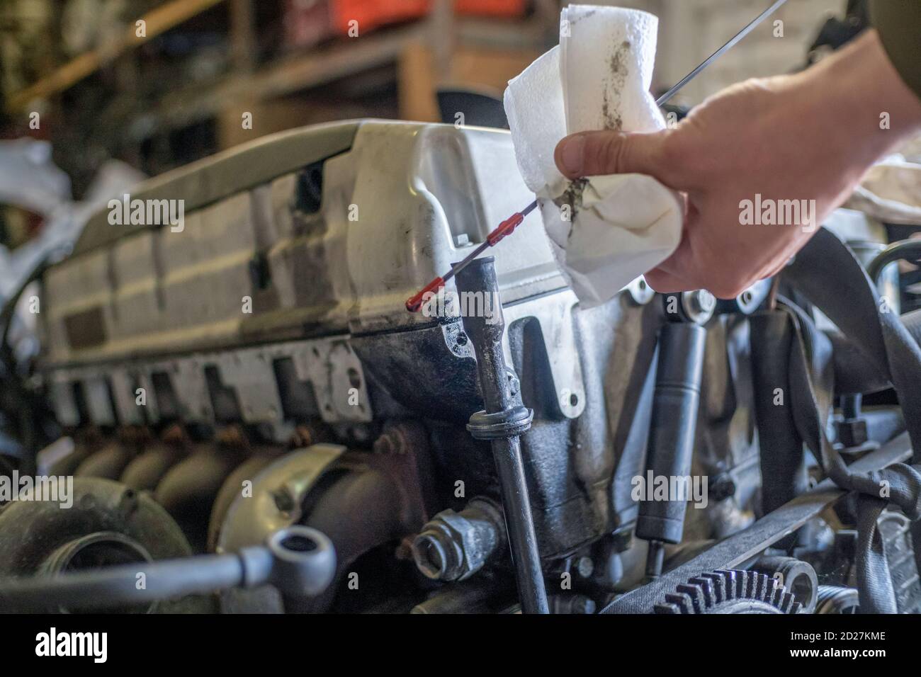 An auto mechanic checks the oil level in a car engine during routine ...