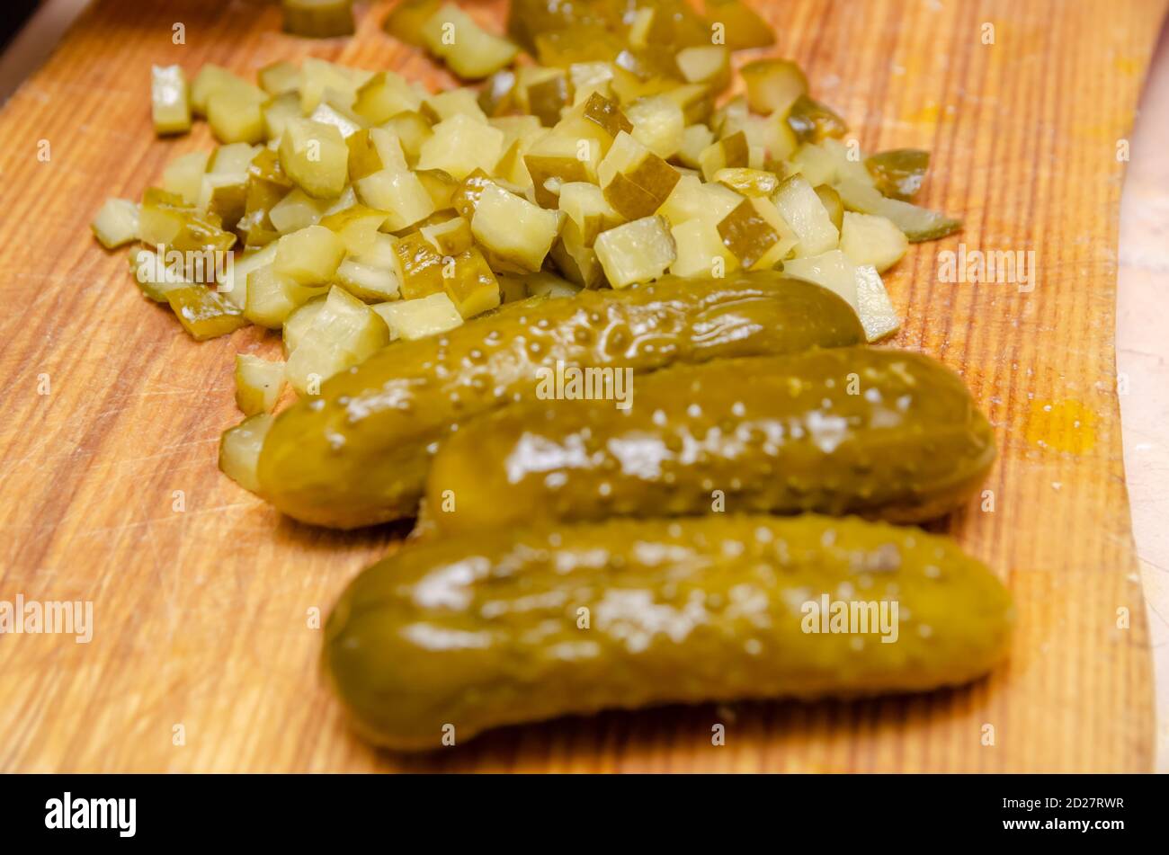 Women's hands cut pickles into cubes on a wooden cutting Board in the ...