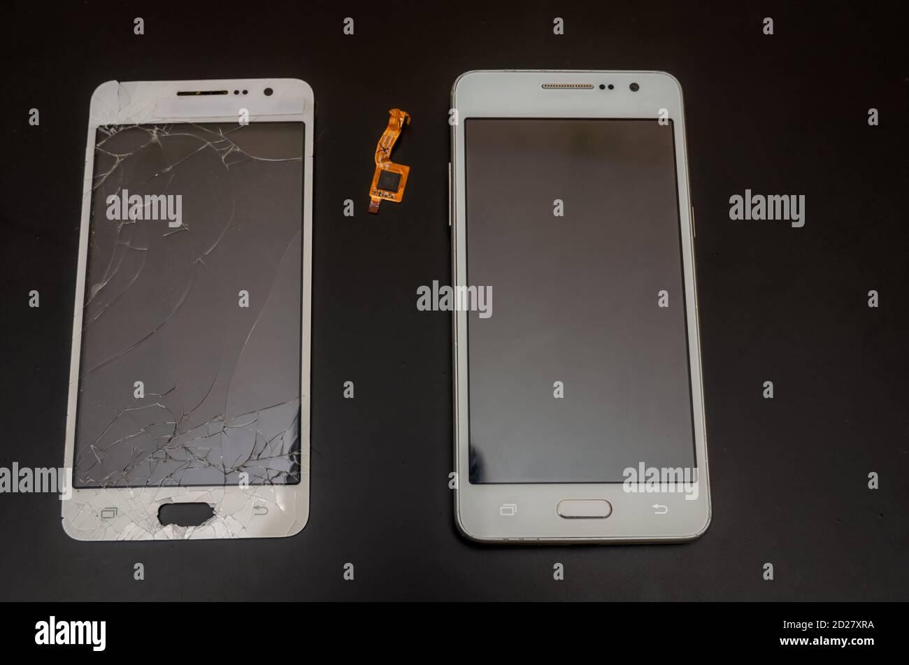 Smartphone after repairing a cracked touch screen. Nearby is a cracked ...