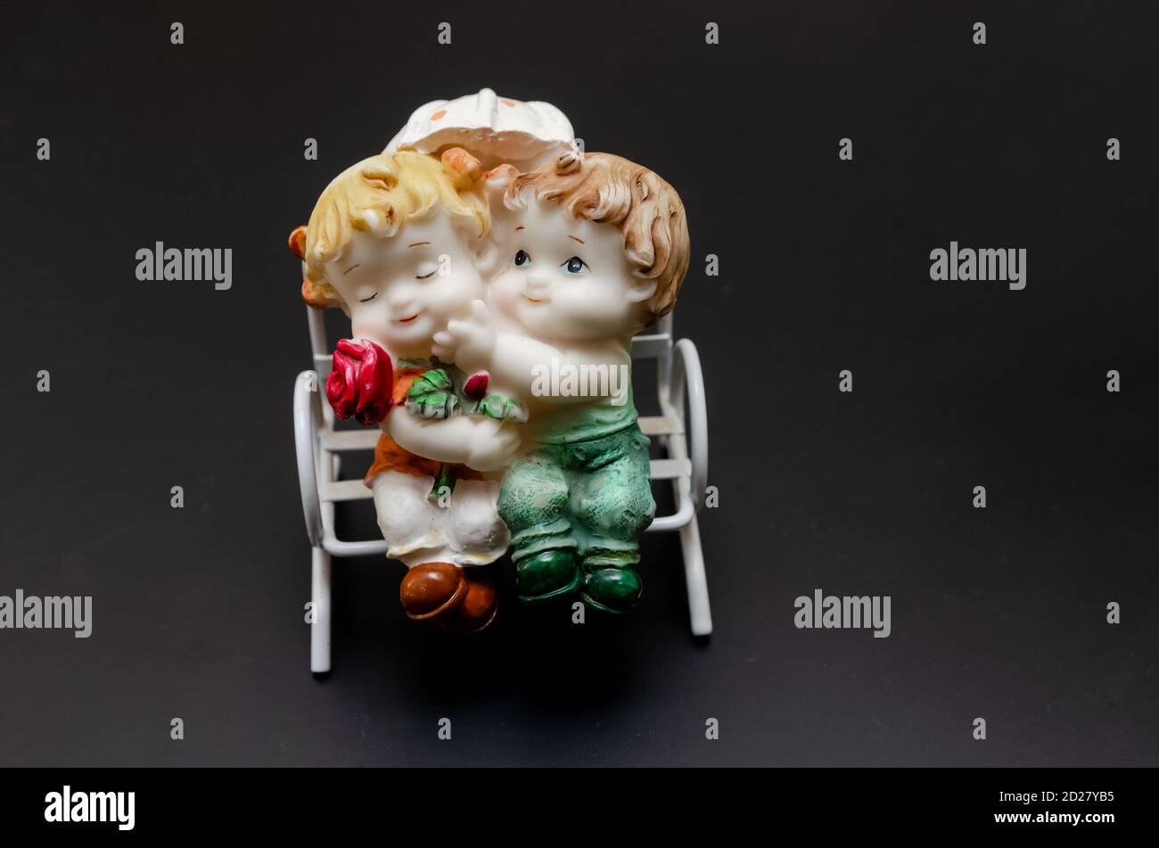 Ceramic figurines of children on a bench on a black background Stock ...