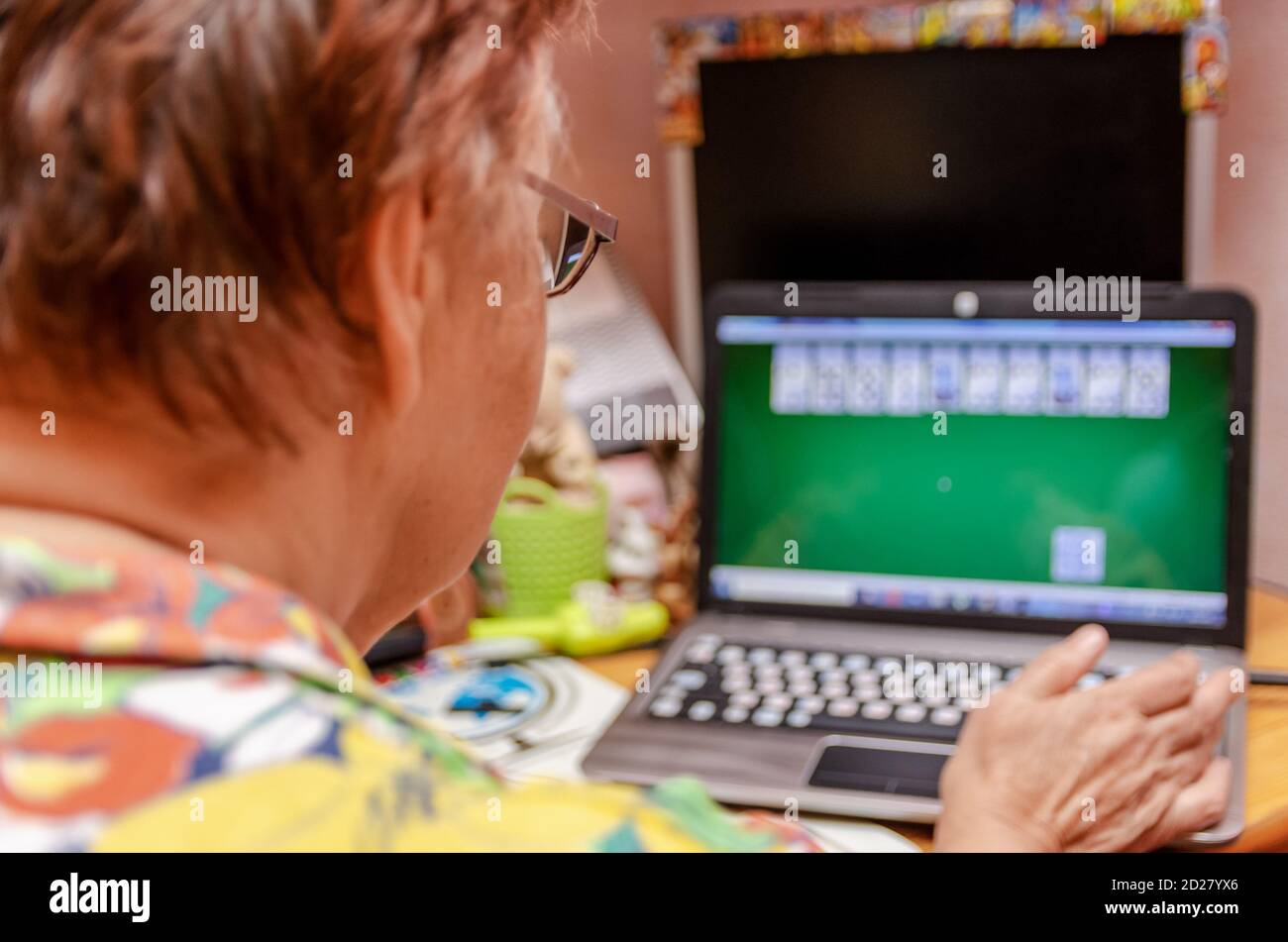 Old woman with glasses plays a computer game on a laptop. Photo from ...