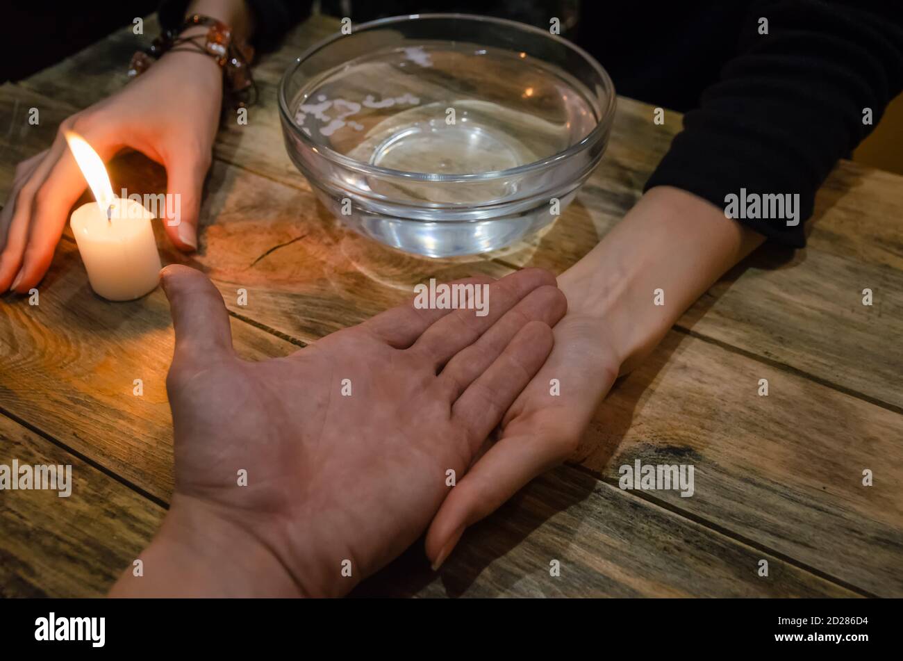Divination with a candle on the water. hand of a fortune teller and the ...