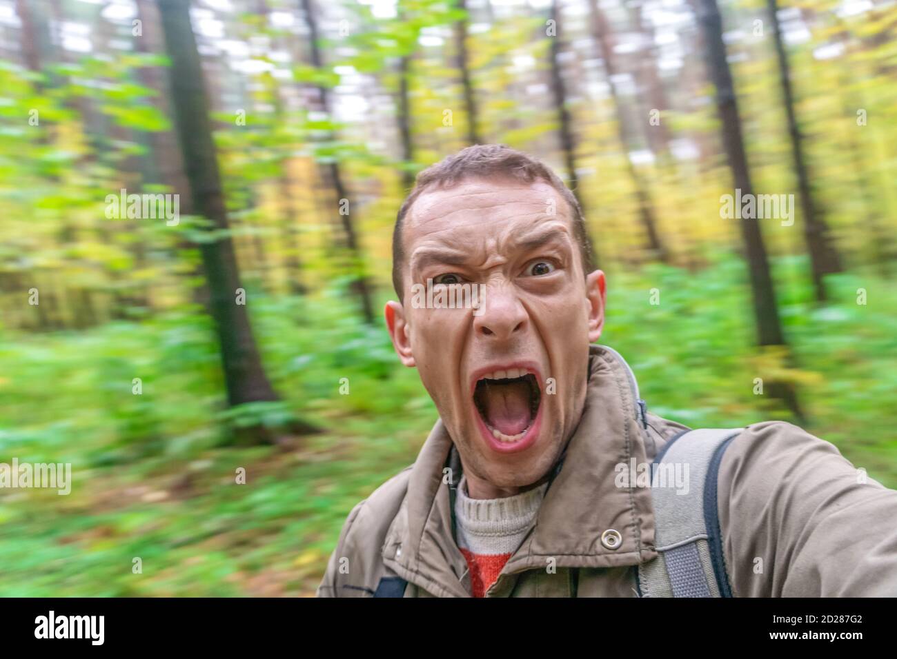 brunette man screaming in the forest in a frightened voice, portrait of ...