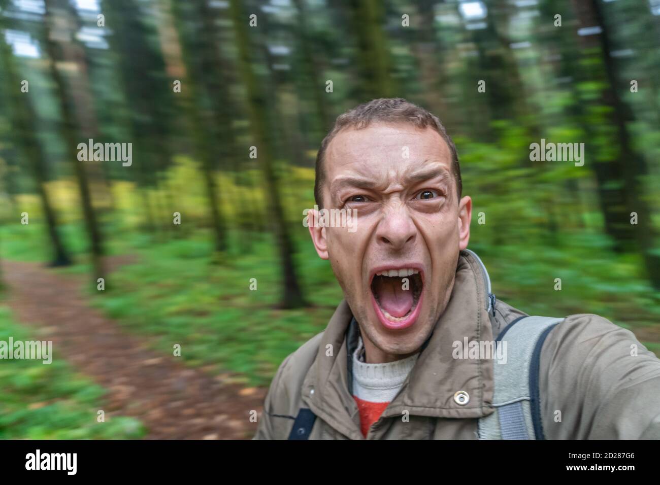 brunette man screaming in the forest in a frightened voice, portrait of ...