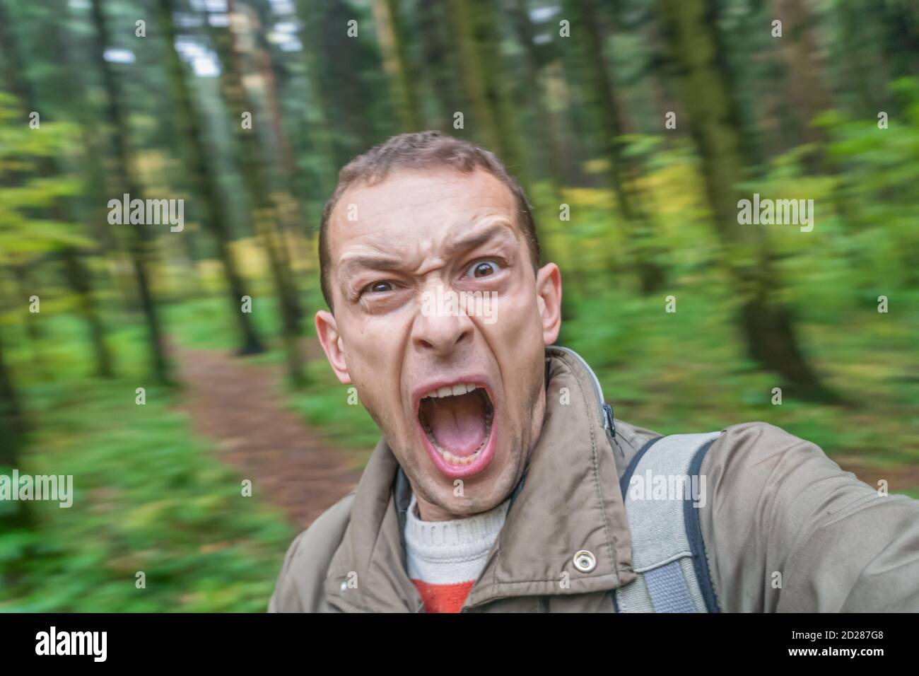brunette man screaming in the forest in a frightened voice, portrait of ...