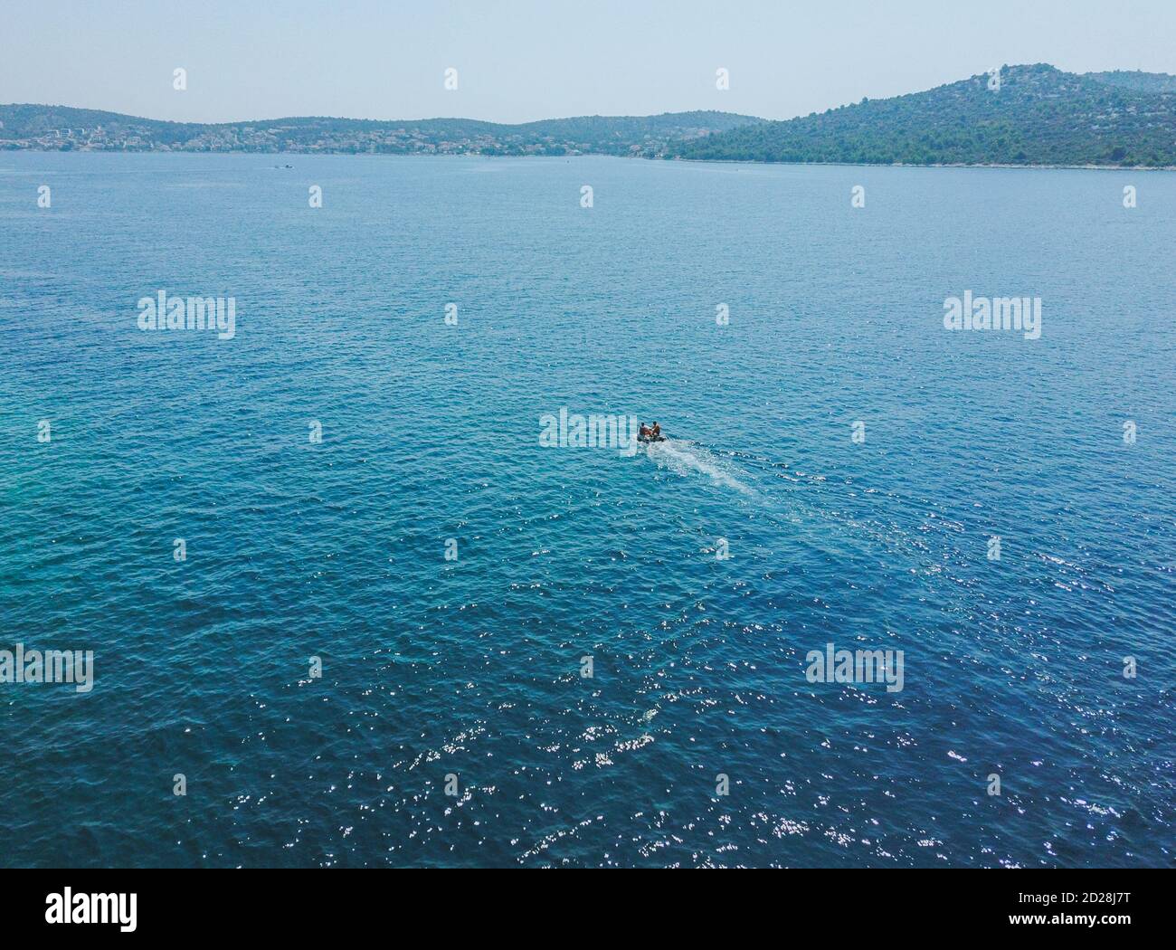 Two people in the rubber dinghy boat moving across deep, blue sea ...