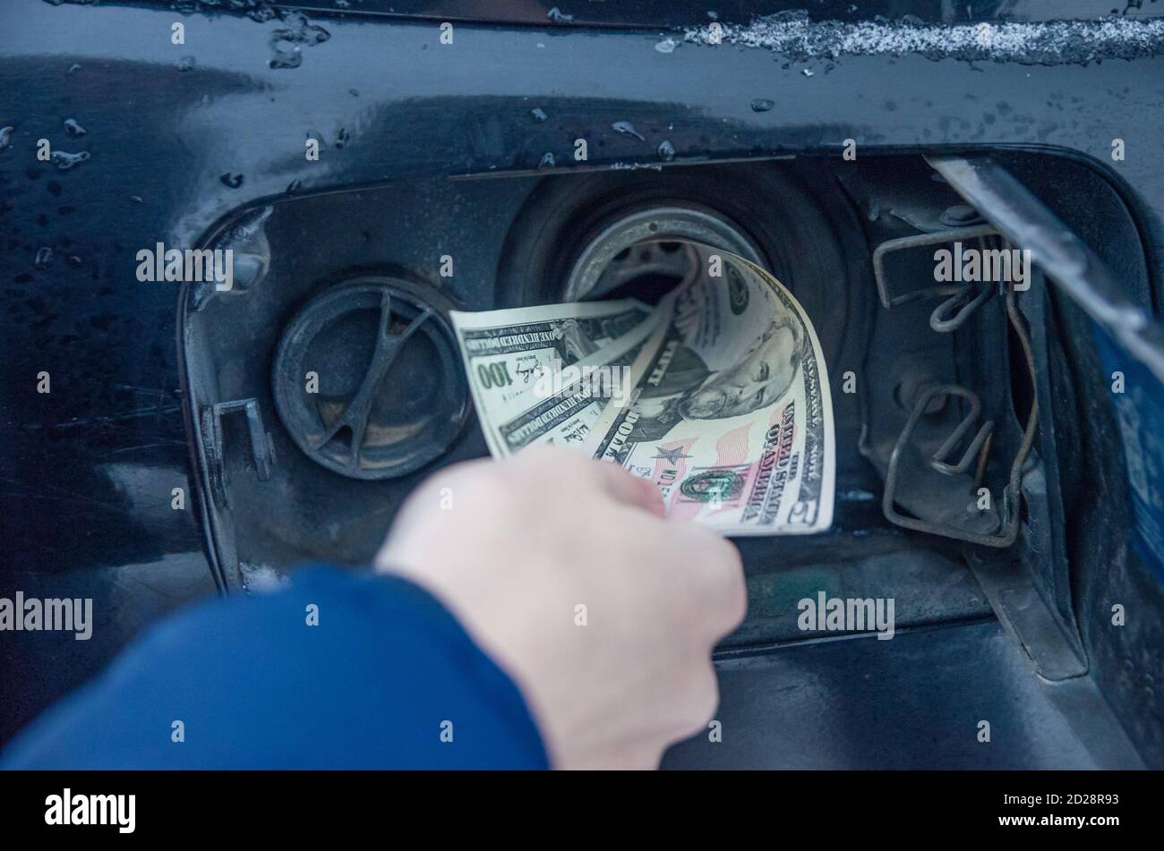 transport costs. hand inserting money dollars in car fuel tank Stock ...