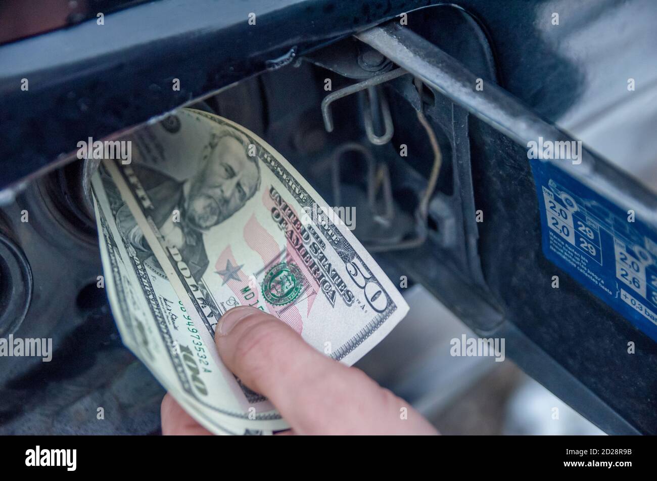 transport costs. hand inserting money in car fuel tank Stock Photo - Alamy