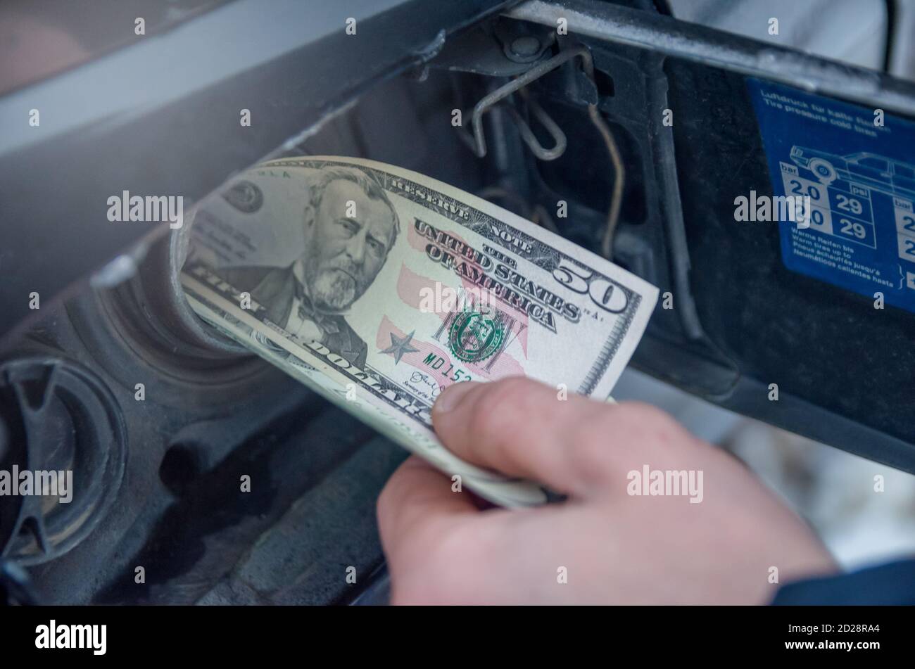 transport costs. hand inserting money dollars in car fuel tank Stock ...