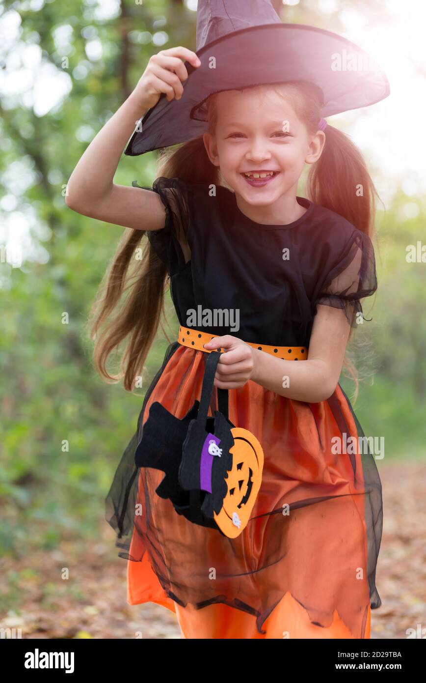 Happy little girl wearing a witch carnival costume and basket for ...
