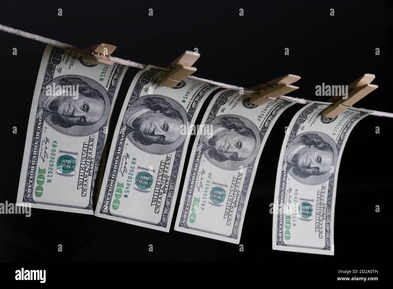 One-hundred dollar bills are hung with clothespins on a string on a ...