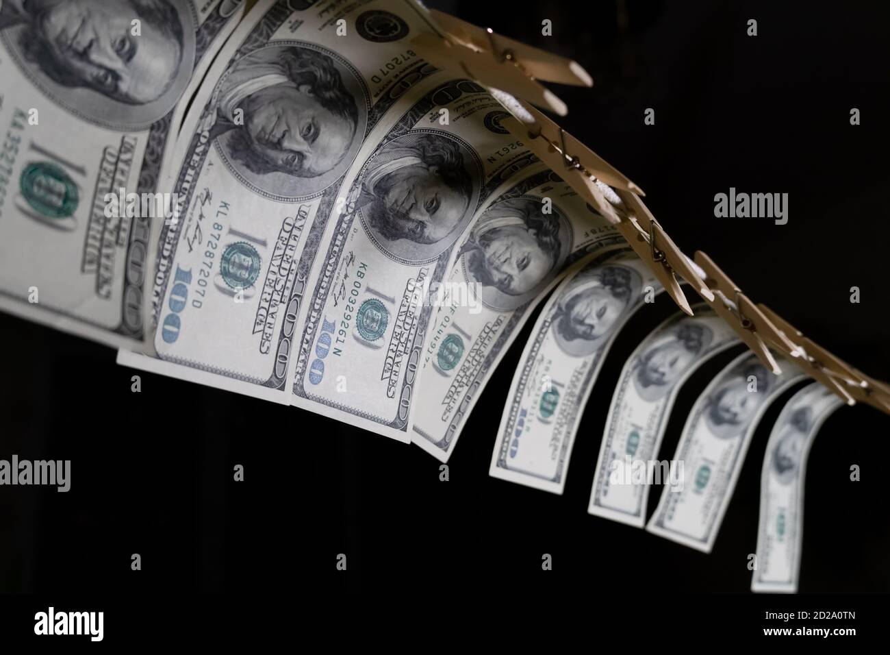 One-hundred dollar bills are hung with clothespins on a string on a ...