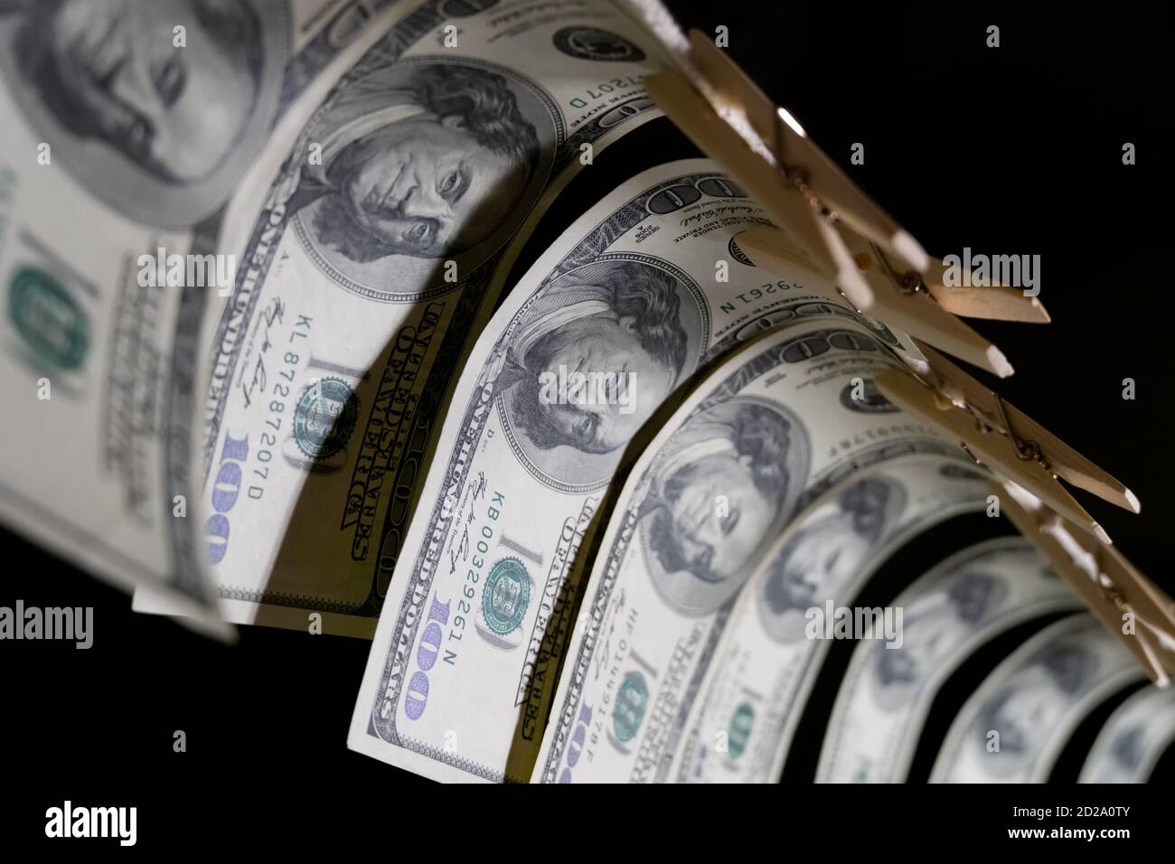 One-hundred dollar bills are hung with clothespins on a string on a ...