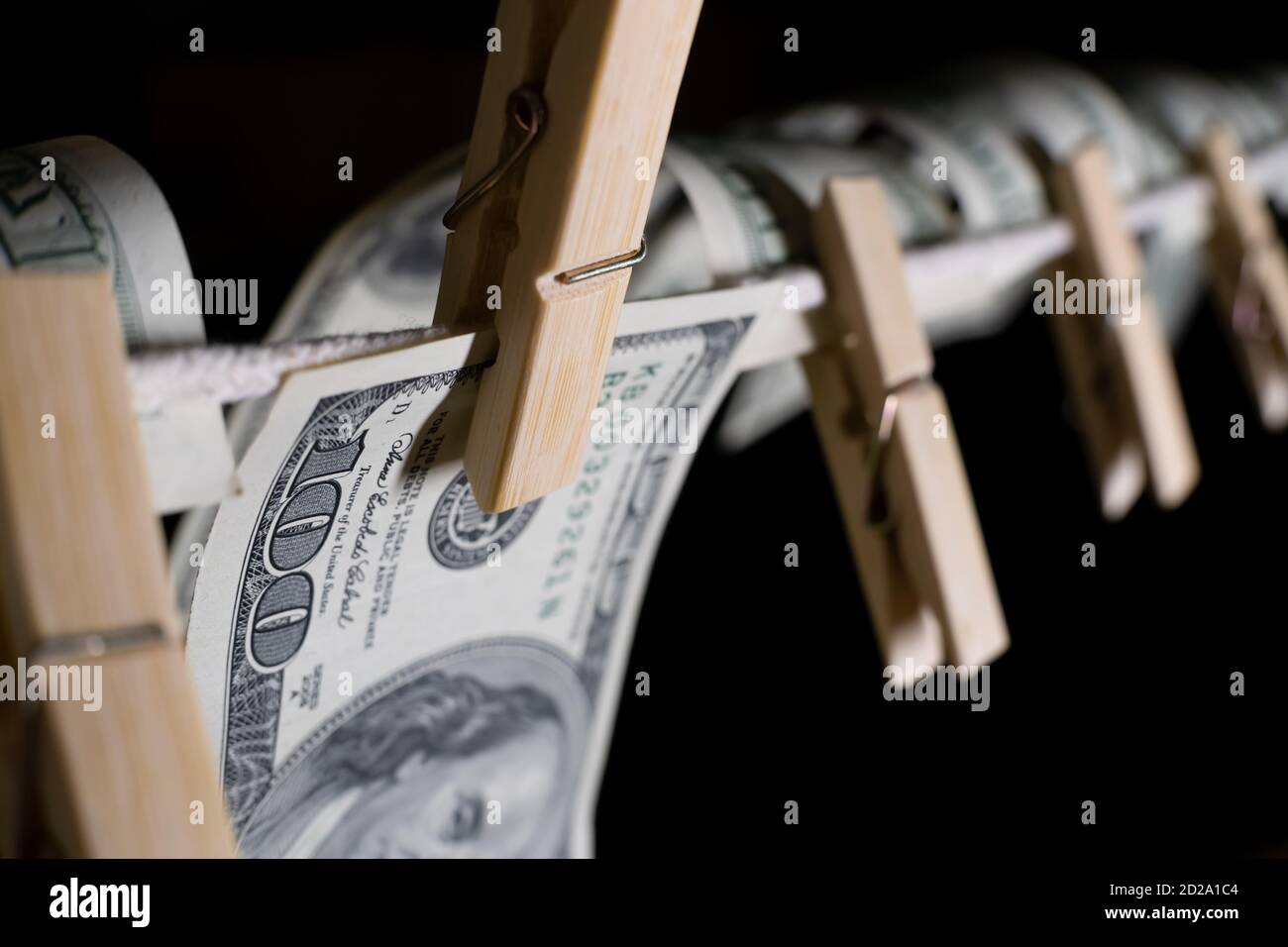 One-hundred dollar bills are hung with clothespins on a string on a ...