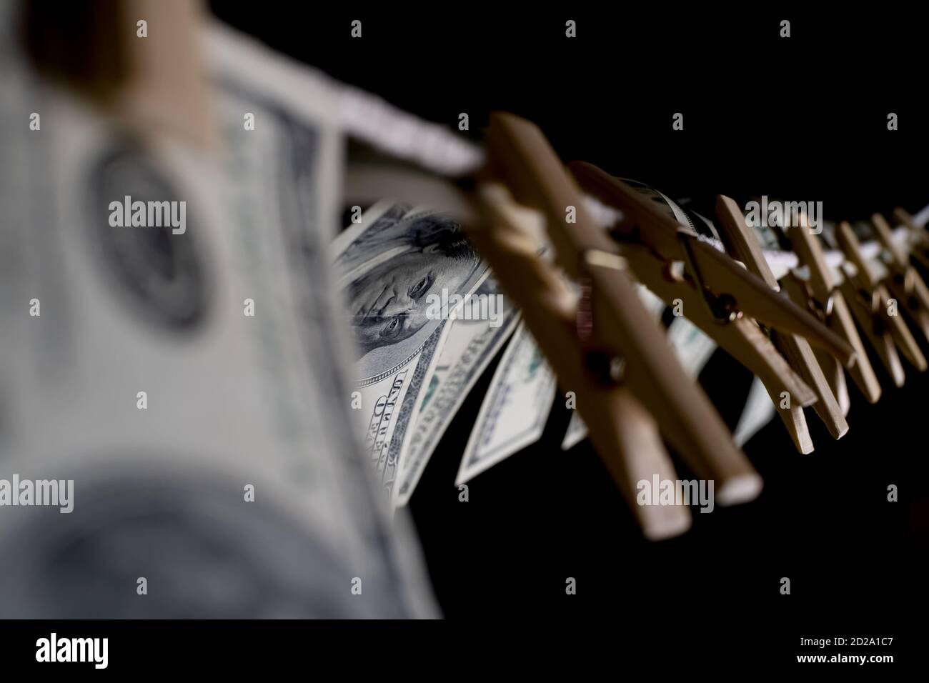 One-hundred dollar bills are hung with clothespins on a string on a ...