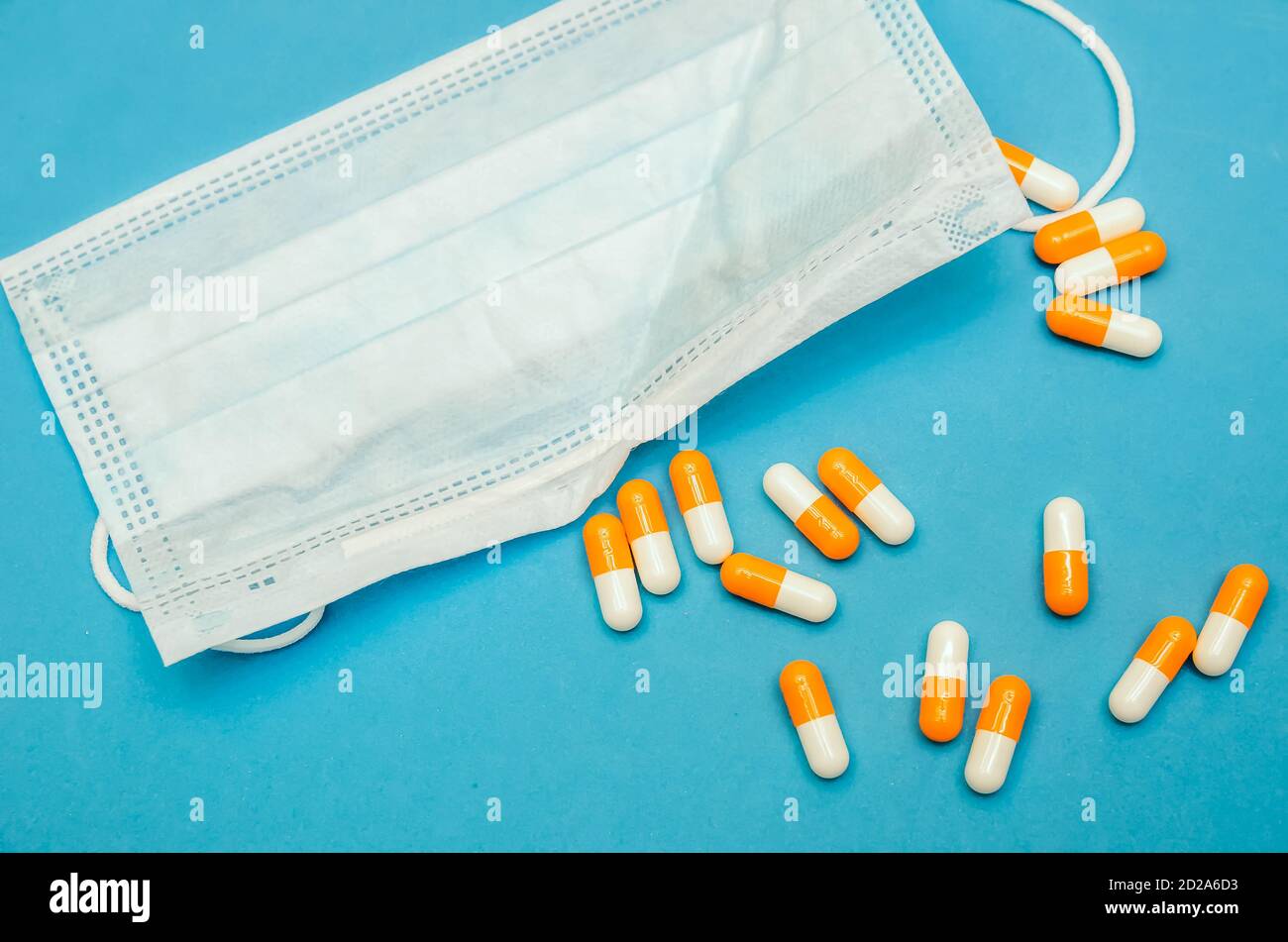 Medical mask, orange-white capsules on a blue background close-up Stock ...