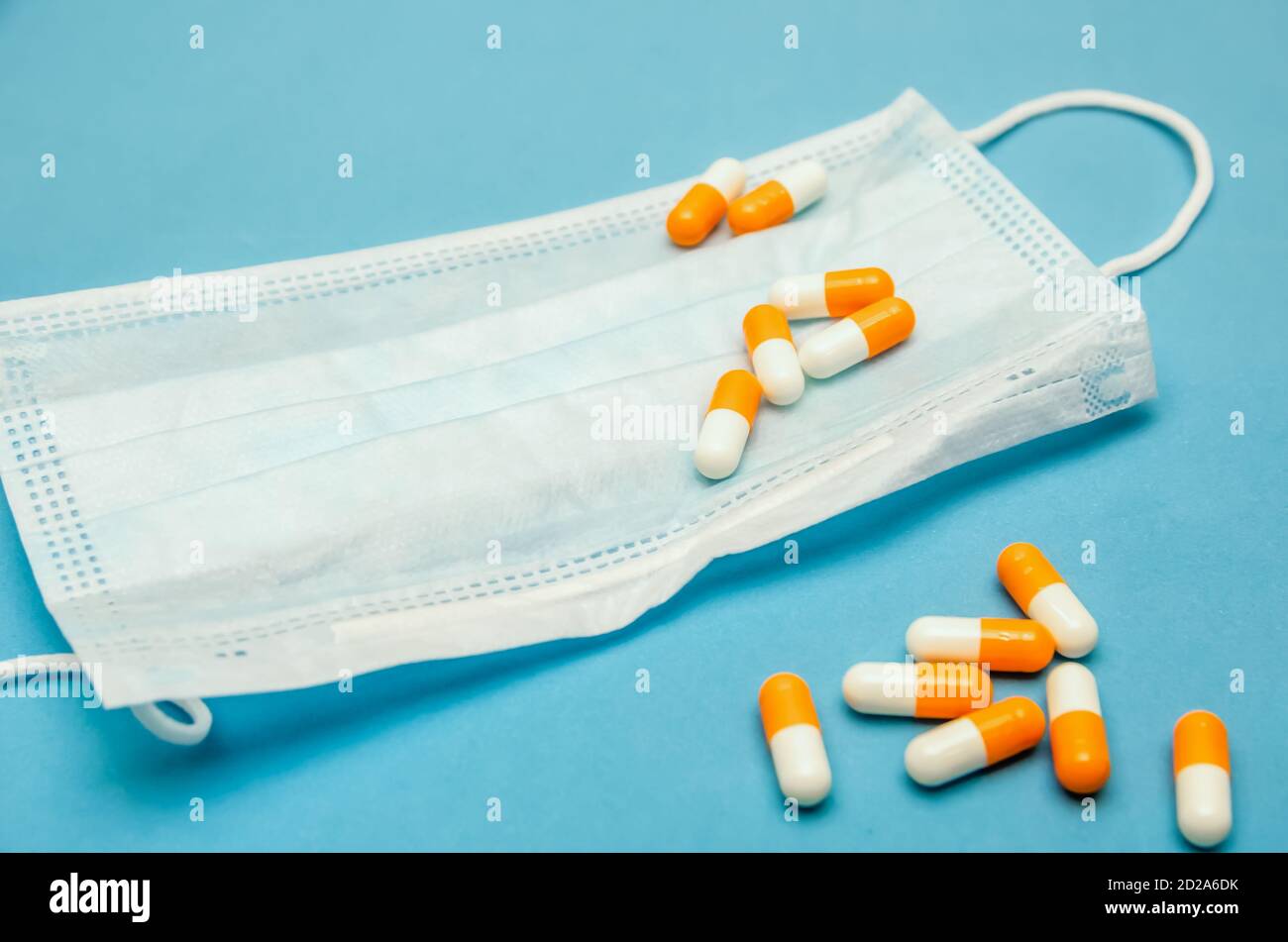 Medical mask, orange-white capsules on a blue background close-up Stock ...