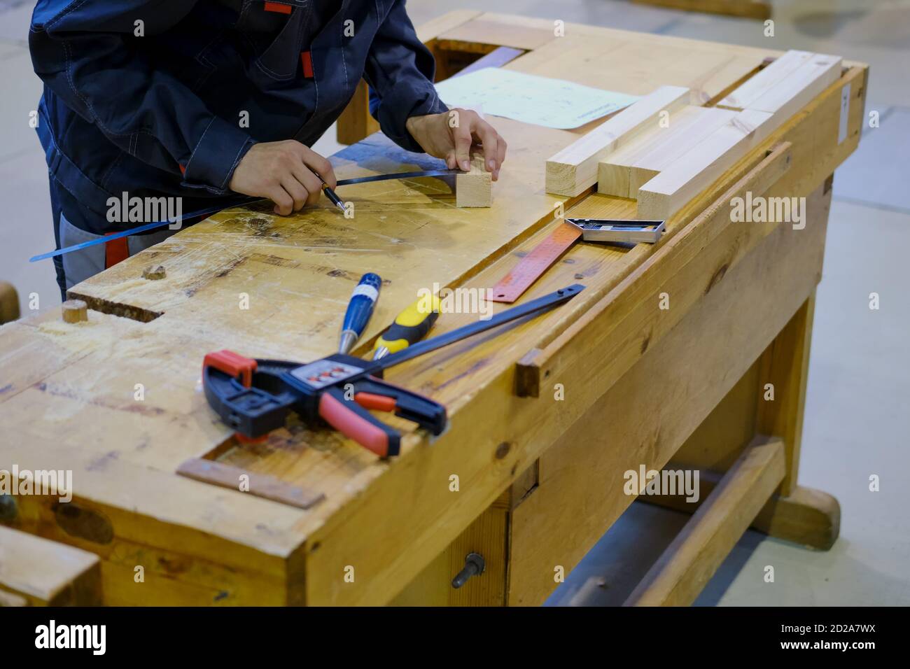 A carpenter measures a bar of wood with a ruler for carpentry on a ...