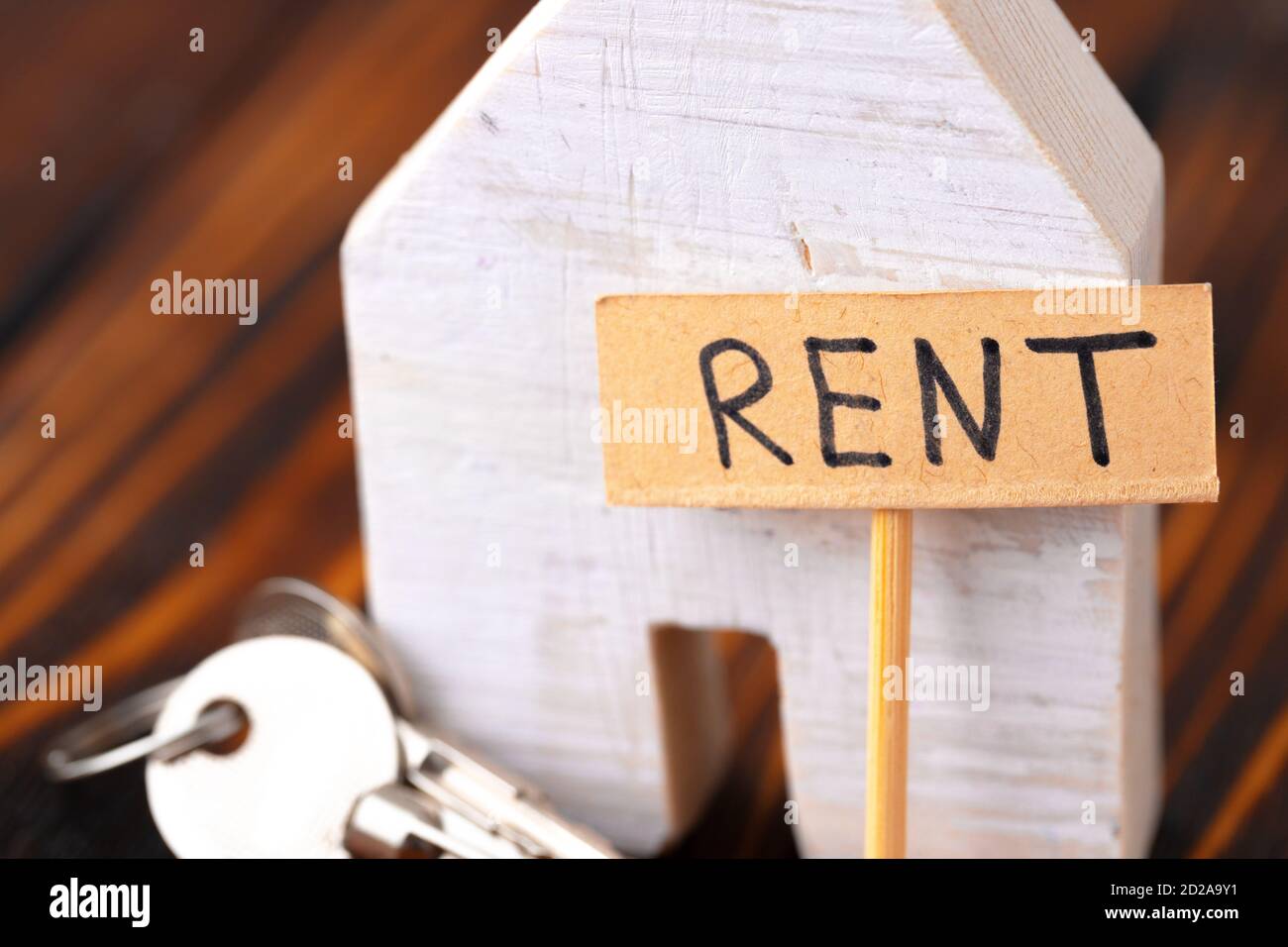 Wooden house model and rent tag sign Stock Photo - Alamy