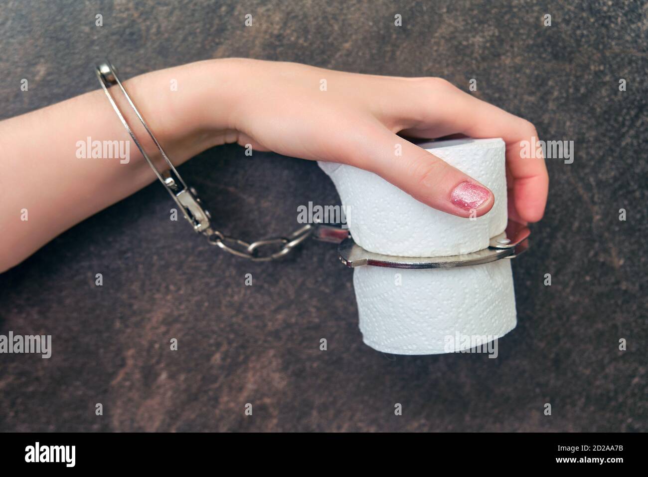 Female hand handcuffed to toilet paper, close-up. Concept of abdominal ...