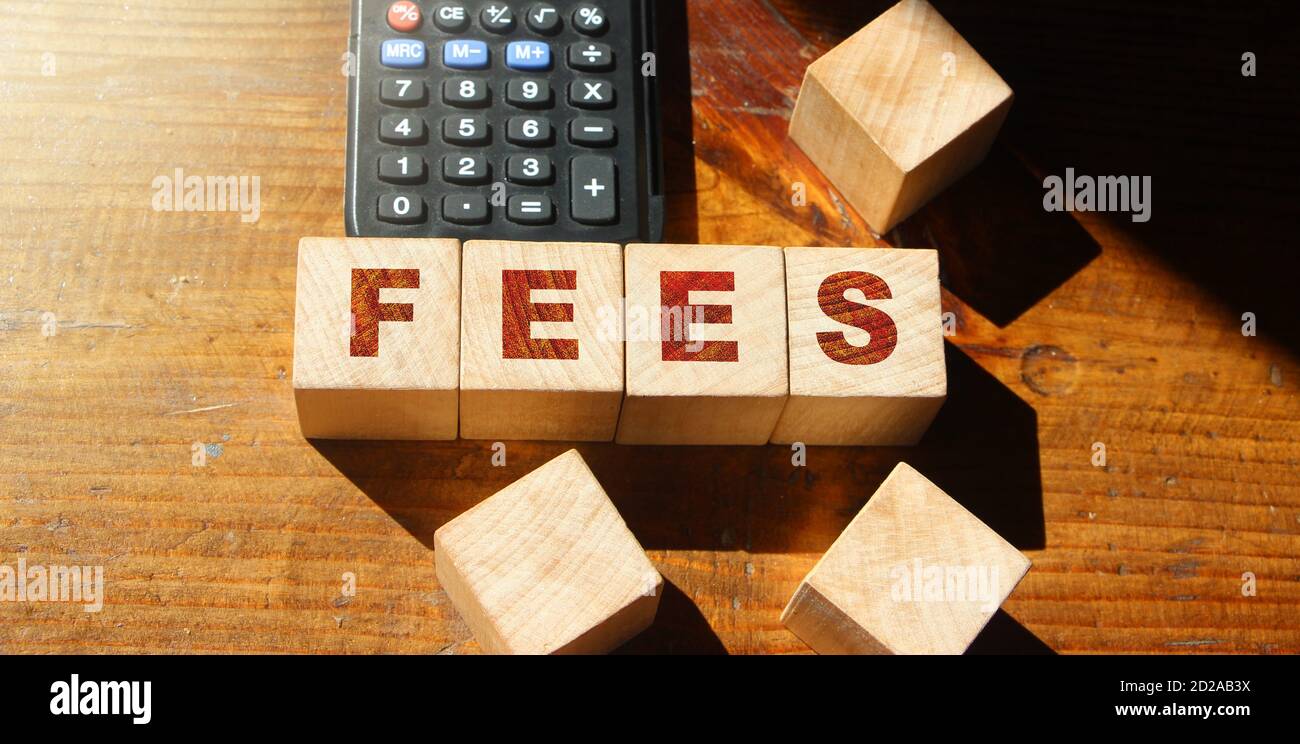 Wooden Blocks with the text: Fees and calculator on wooden table. Taxes ...