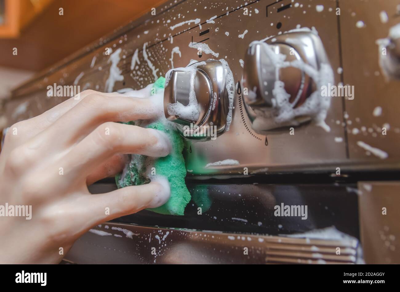 woman's hand washes a green sponge with foam on the switch handle of a ...