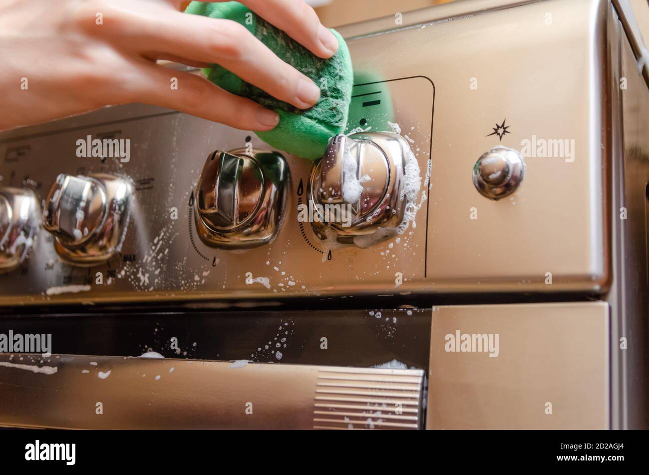 woman's hand washes a green sponge with foam on the switch handle of a ...