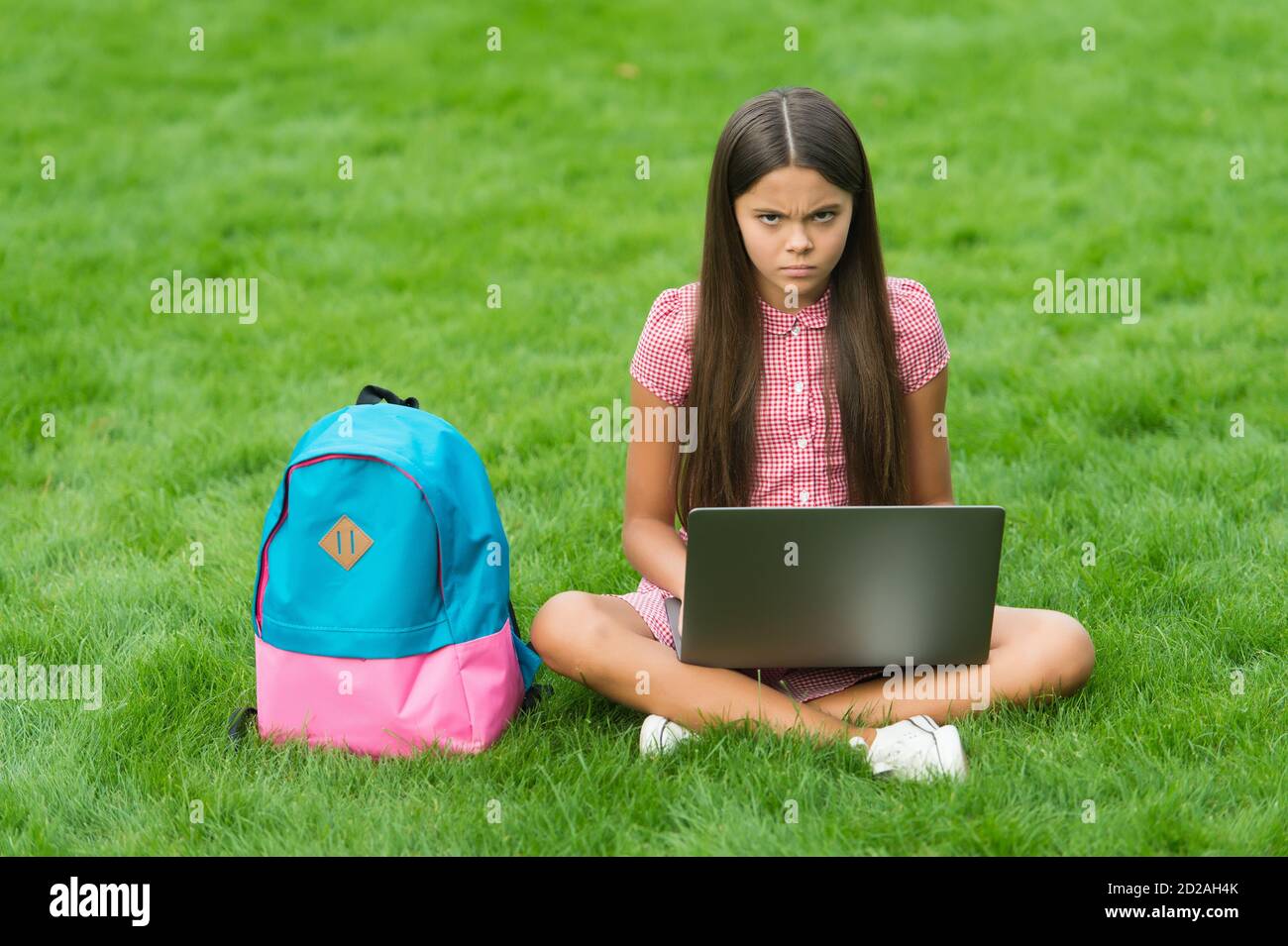 upset kid while using computer sit on green grass in park with school ...
