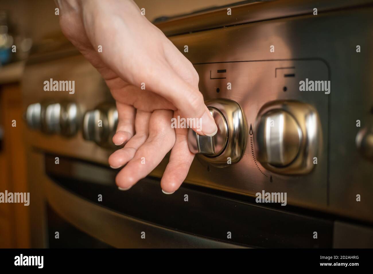 woman's hand turns on a switch on a stainless steel gas stove close up ...
