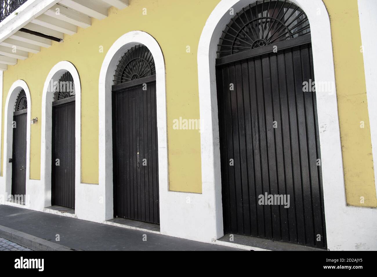 Yellow building house facade with brown wooden doors and arch outdoor ...