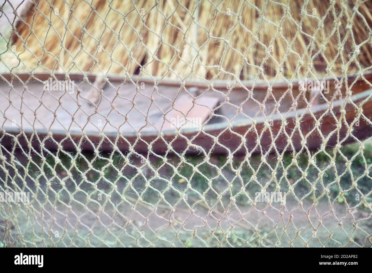 Large net for catching fish, close-up. An old fishing boat behind a net ...