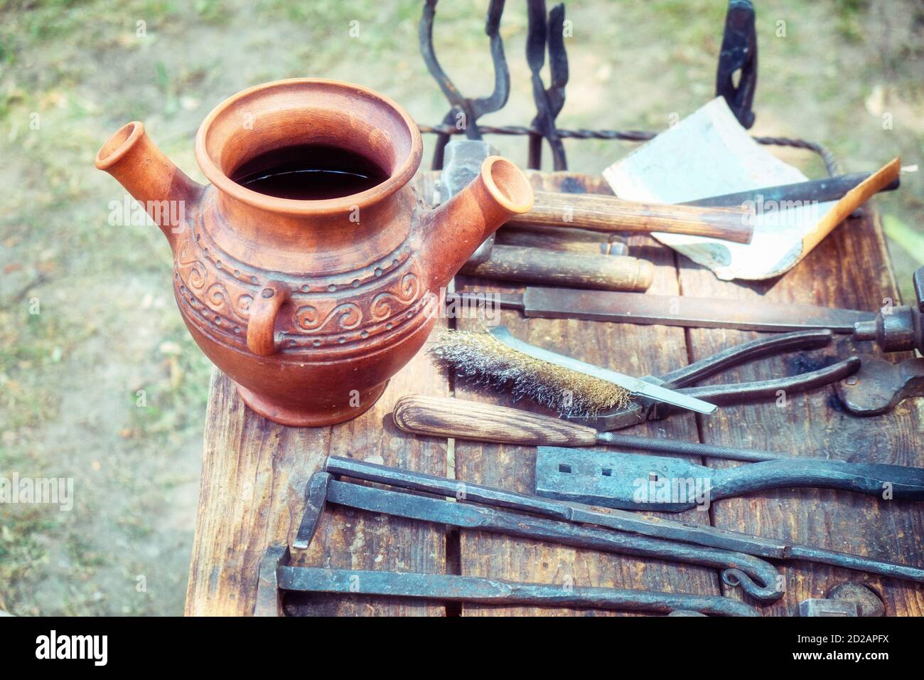 Retro blacksmith tools on wooden table in forge. Pitcher for hardening ...